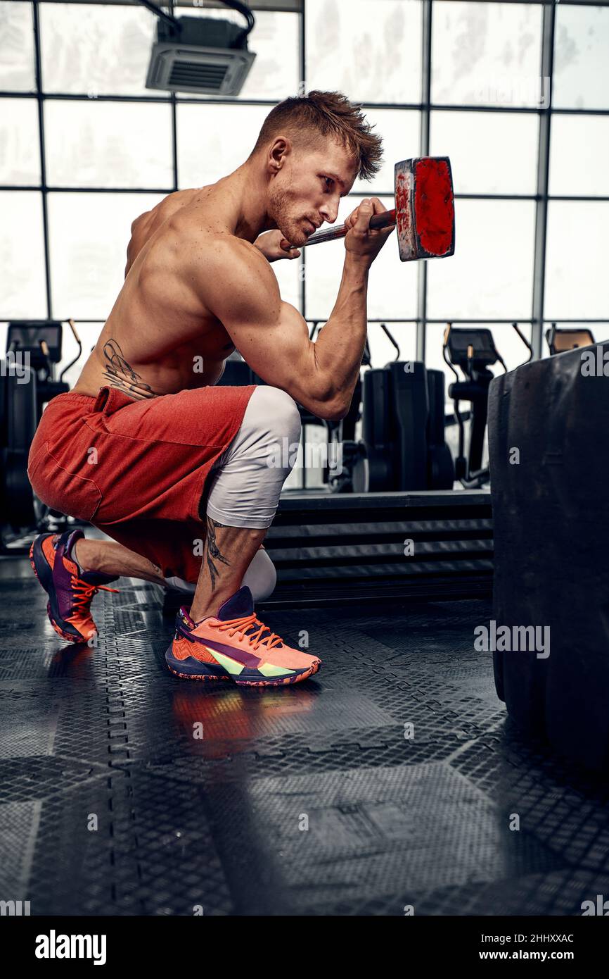 Strength concept. Male athlete using hammer during fitness workout ...