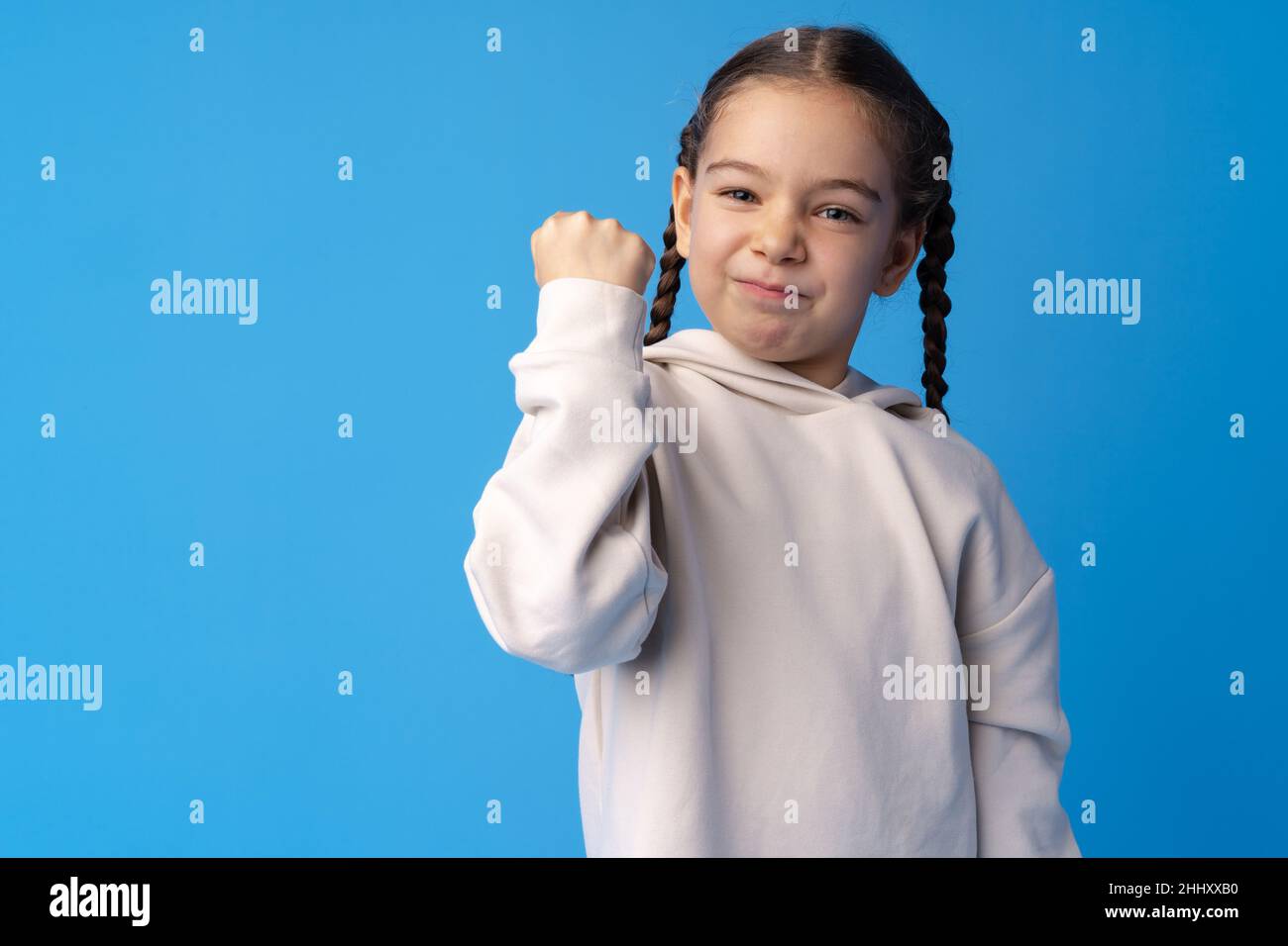 Little cute girl showing her strength on blue background Stock Photo ...