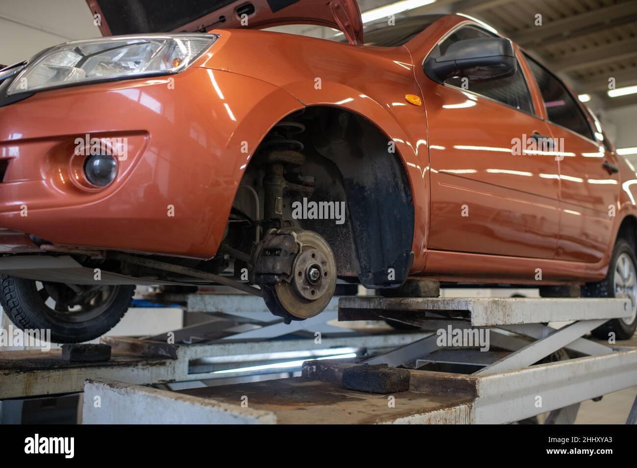 Side part of broken car of light brown color without one wheel standing ...