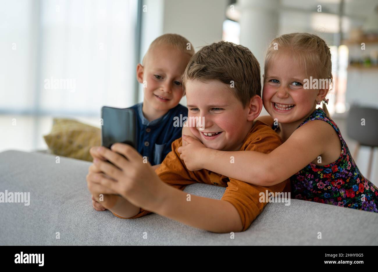 Portrait of children playing on mobile phone together at home. Internet ...