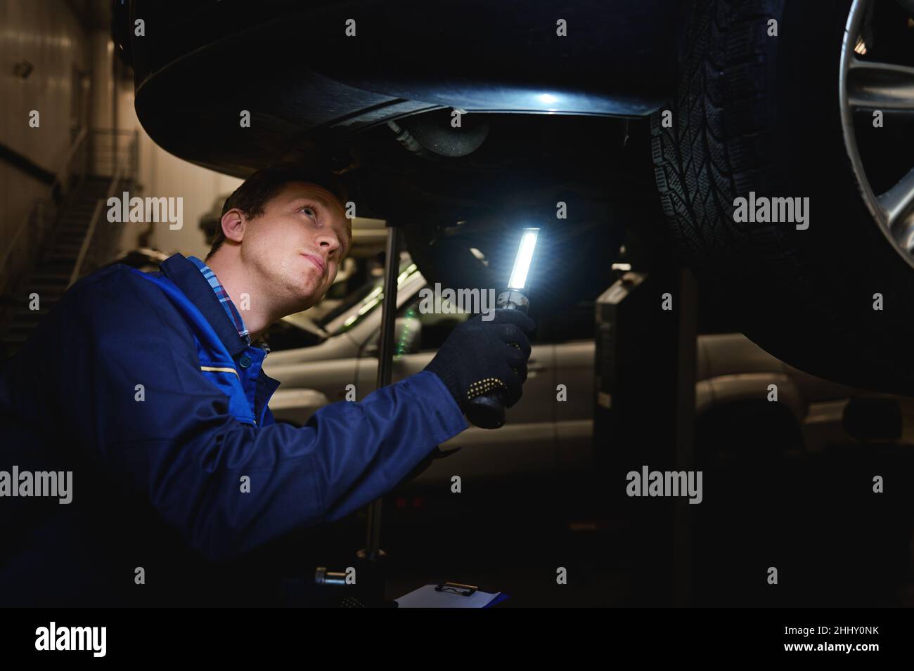 Car mechanic at the inspection checks underbody protection of the car ...