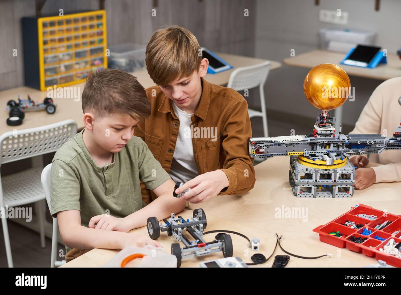 Two boys sitting at the table and constructing the car together during ...