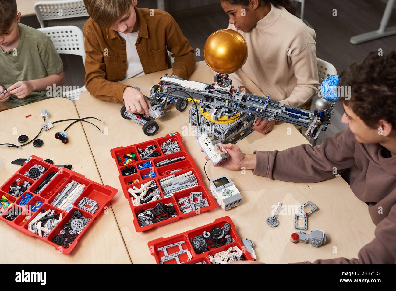 Group of children sitting at the table with constructor and projecting ...