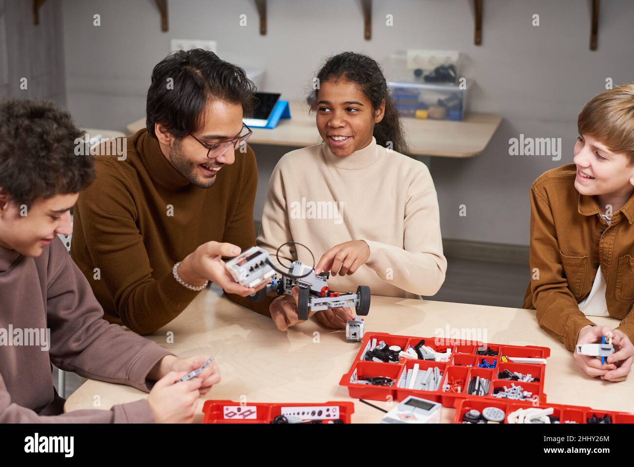 Clever school children with young male teacher investigating electronic ...