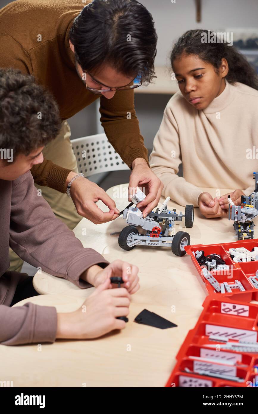 Young teacher showing to children how to build the robot car at the ...