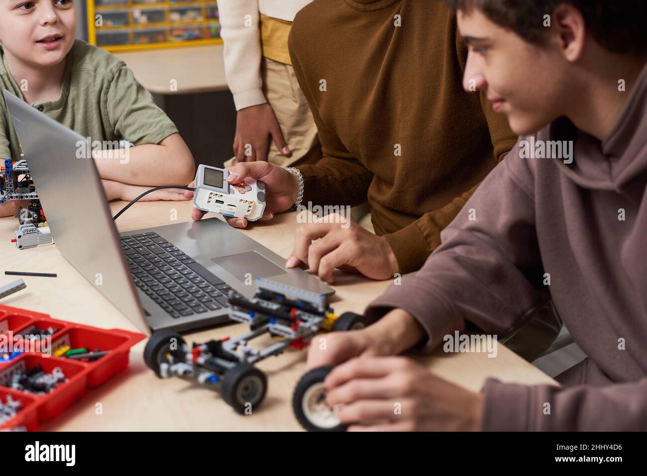 Close-up of teenagers using laptop at the table during their teamwork at robotics lesson Stock ...