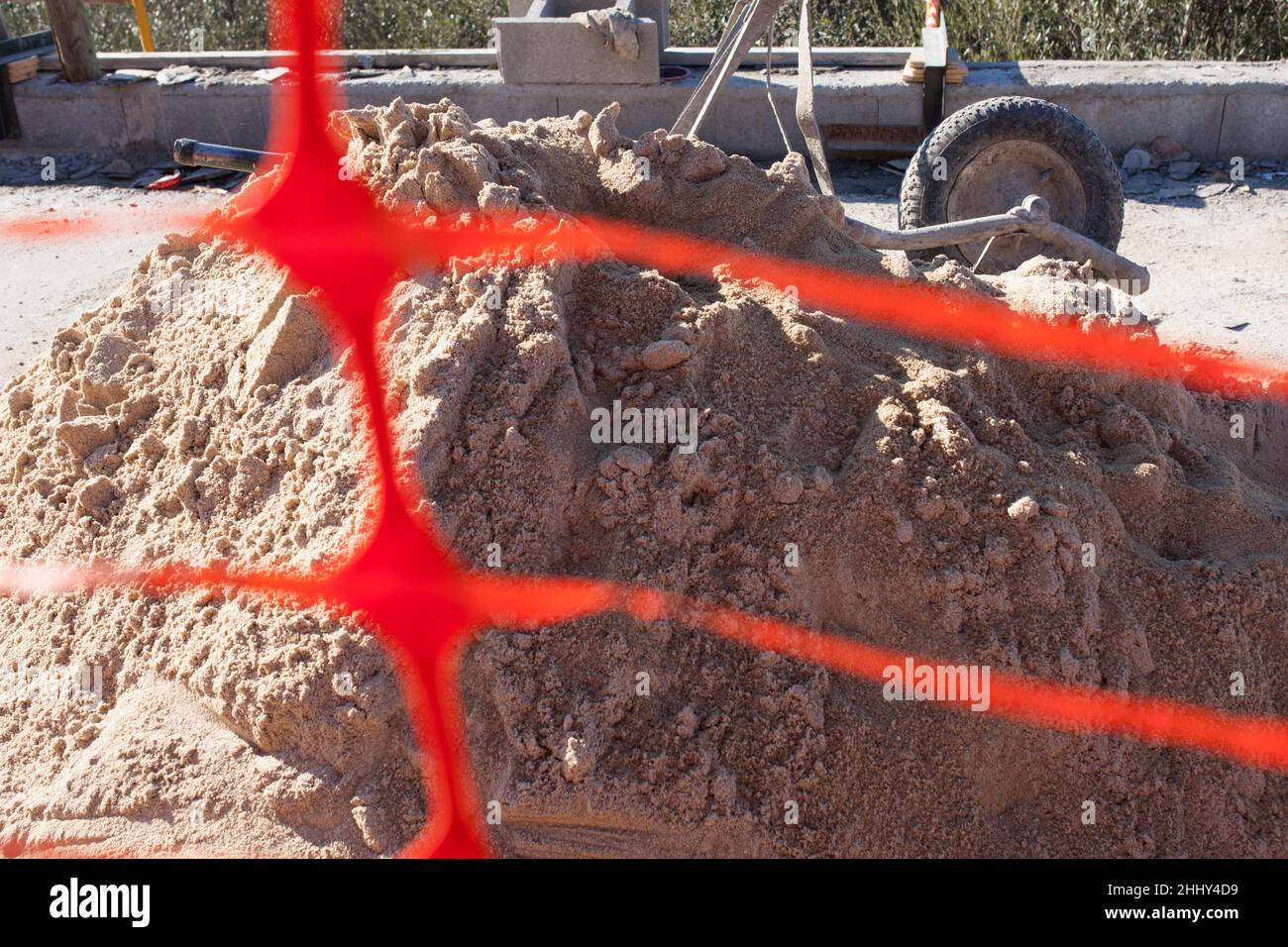 Wheelbarrow turned over sand heap. Footpath construction site protected ...