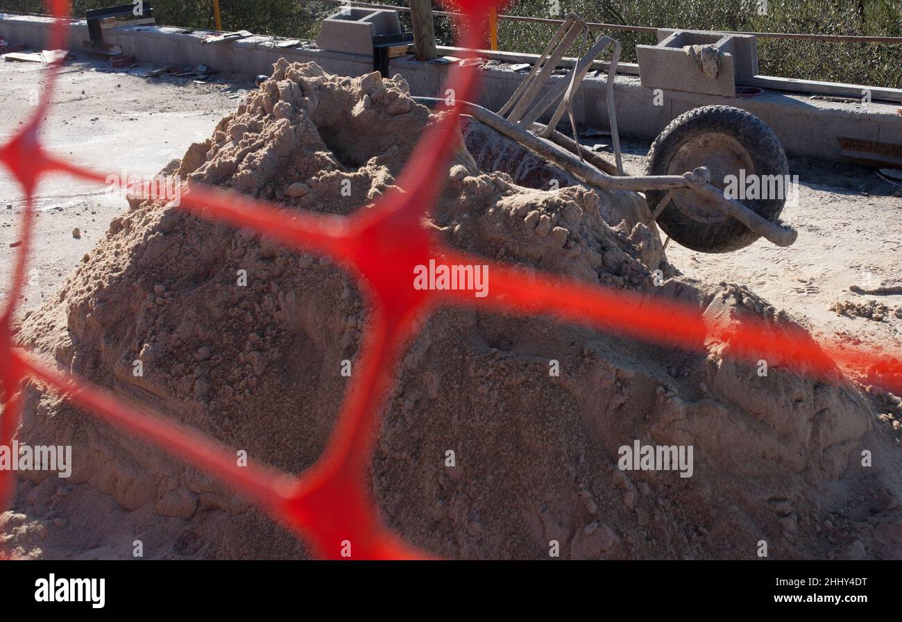 Wheelbarrow turned over sand heap. Footpath construction site protected ...