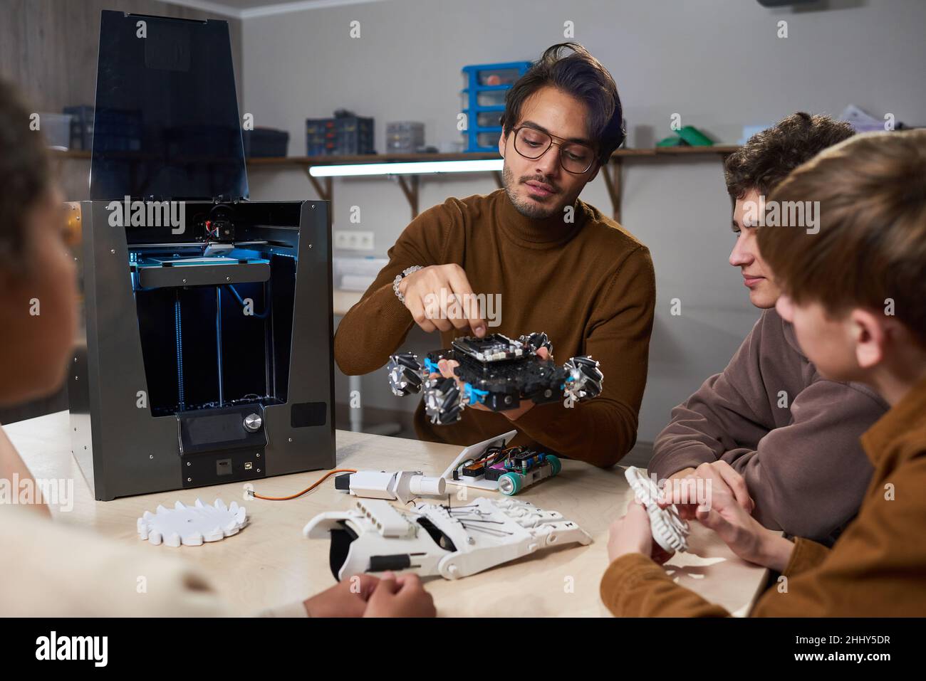 Young teacher showing his students how to build robotic machine while ...