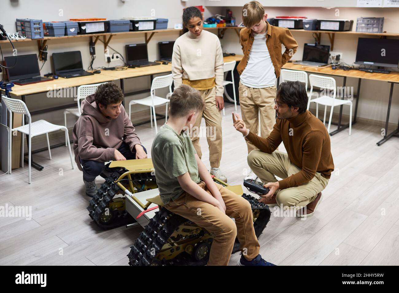 Young teacher explaining the work of robotic machine to his students ...