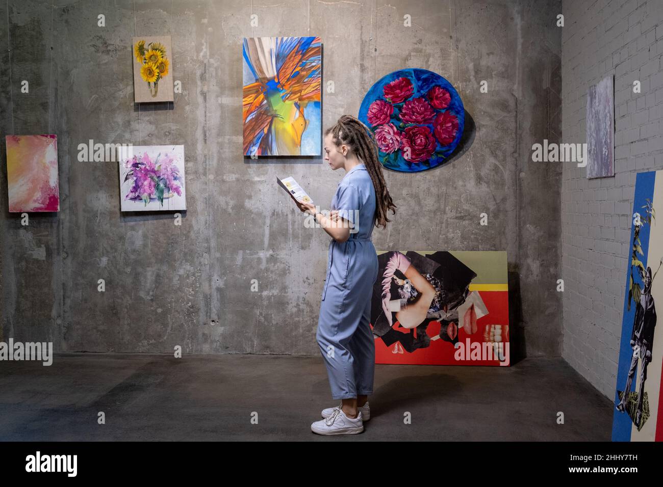Young woman reading a booklet while standing in art gallery with ...