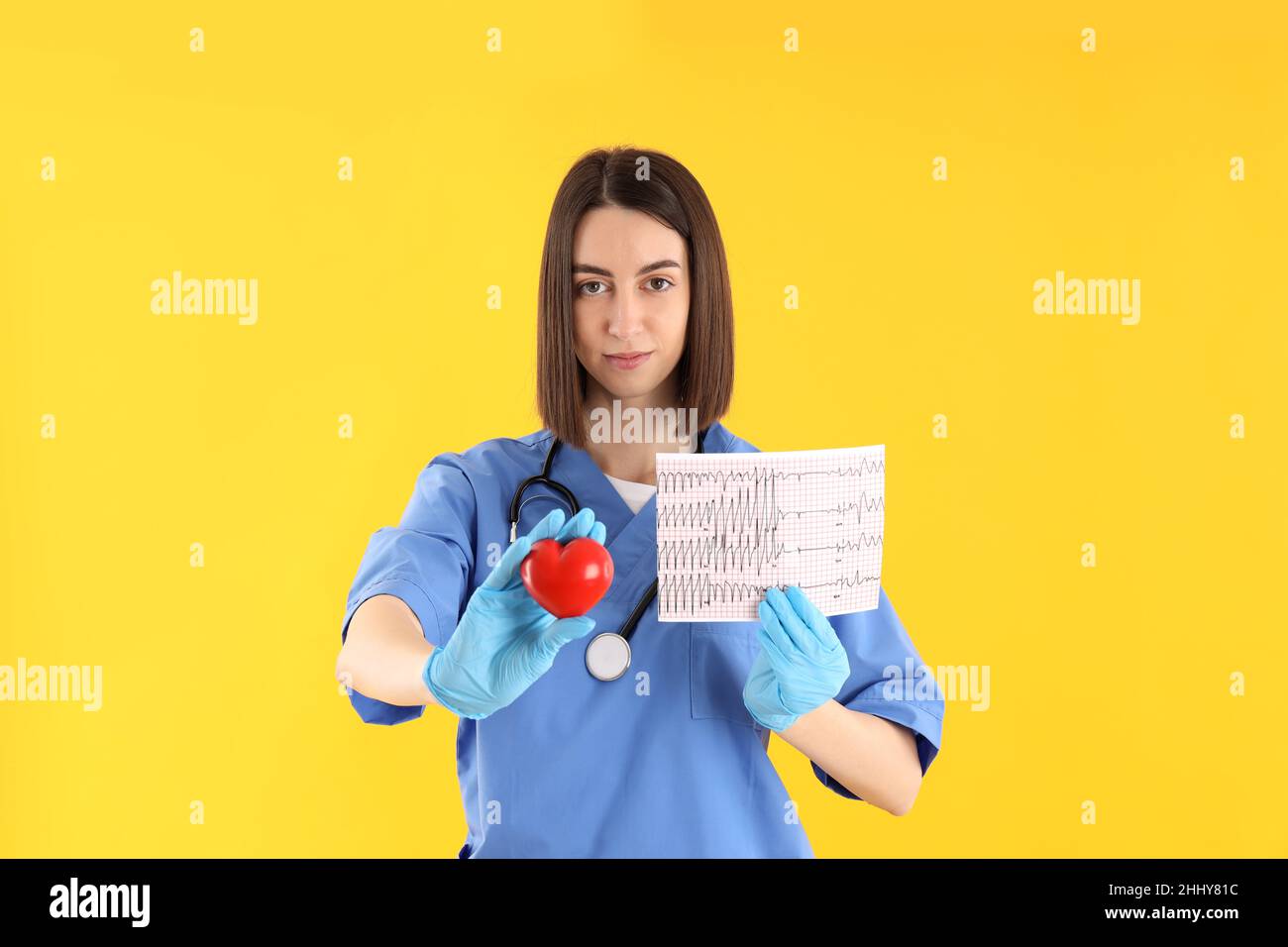 Female trainee nurse with heart and ecg on yellow background Stock ...