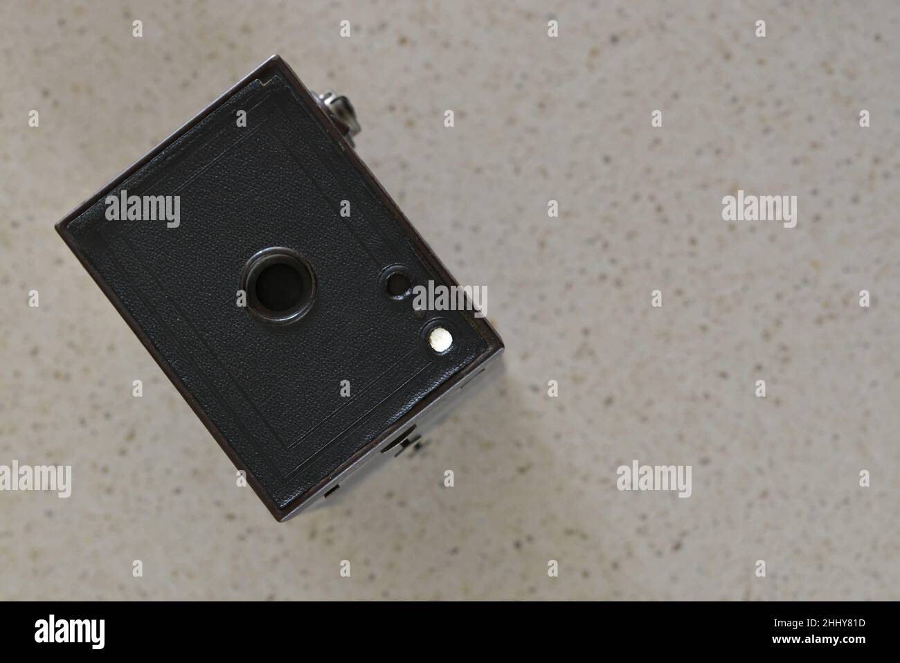 Old box film camera - black. Vertical view of camera front on beige ...