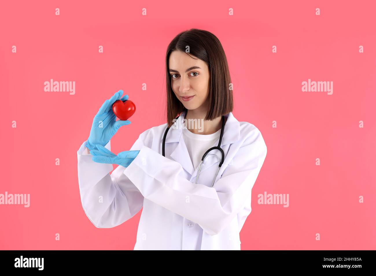 Female trainee doctor with heart on pink background Stock Photo - Alamy