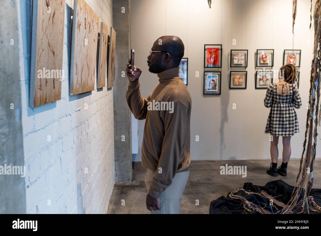 African young man photographing artwork on his mobile phone while ...