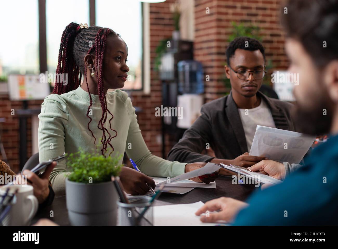 Diverse team sharing papers with marketing strategy analyzing company ...