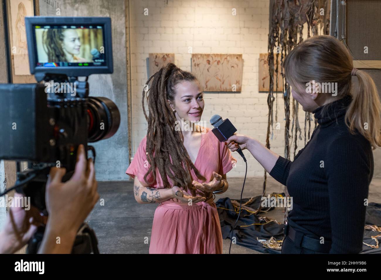 Young artist giving an interview to reporter in honor of the opening of ...