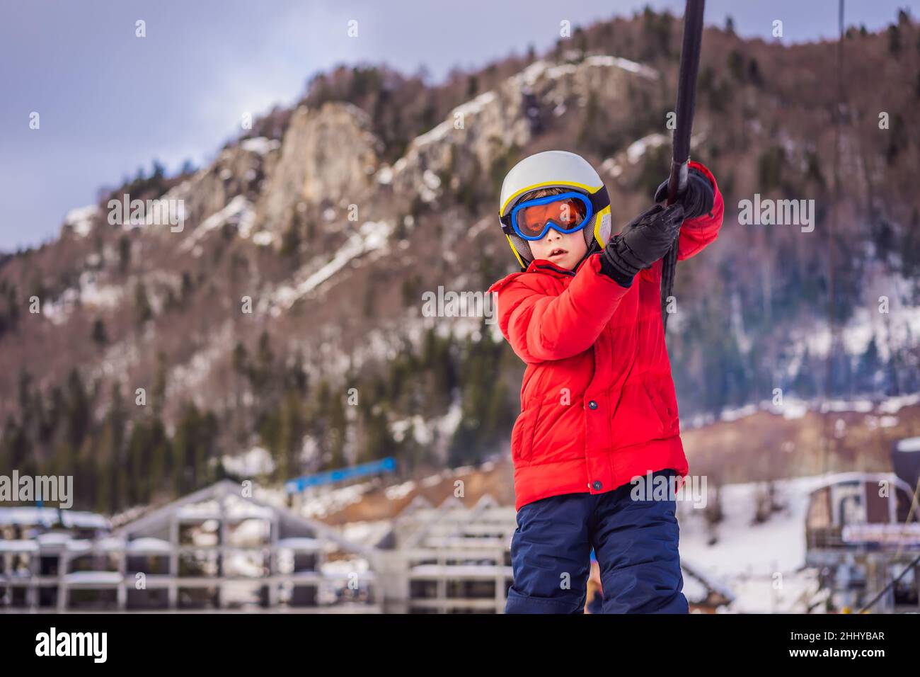 Boy uses a training lift. Child skiing in mountains. Active toddler kid ...