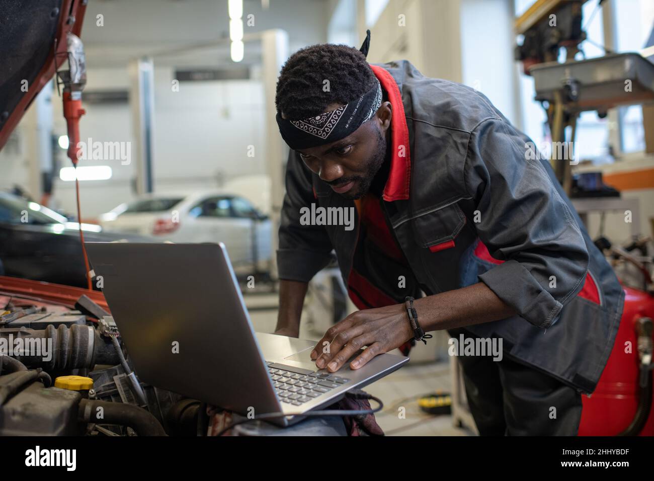 Young African repairman in workwear consulting websites while checking ...