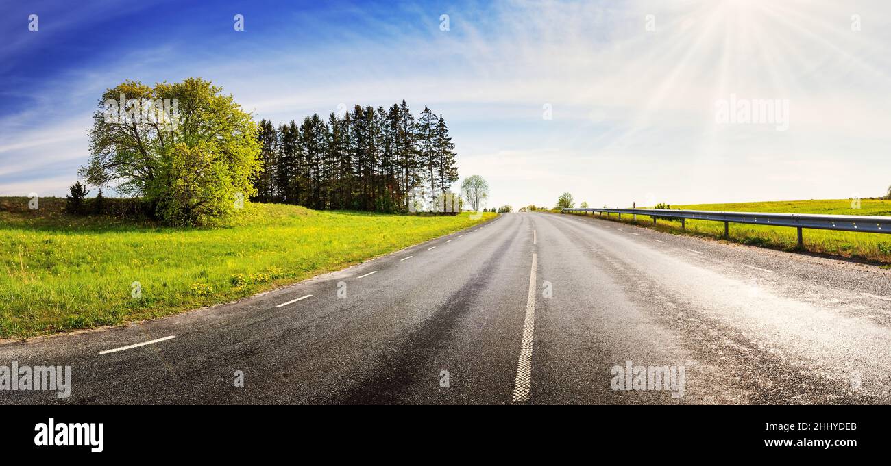 Panoramic view of the asphalt road with beautiful trees and with field ...