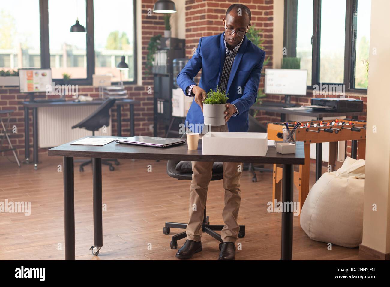 Business man packing up office things in box after getting fired from ...