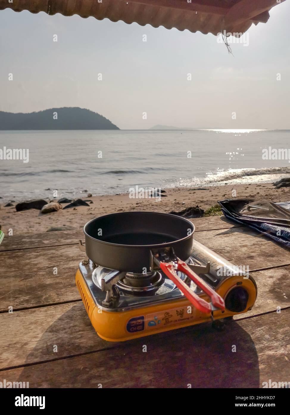 Portable tourist gas stove and cooking pan on wooden table at sandy ...