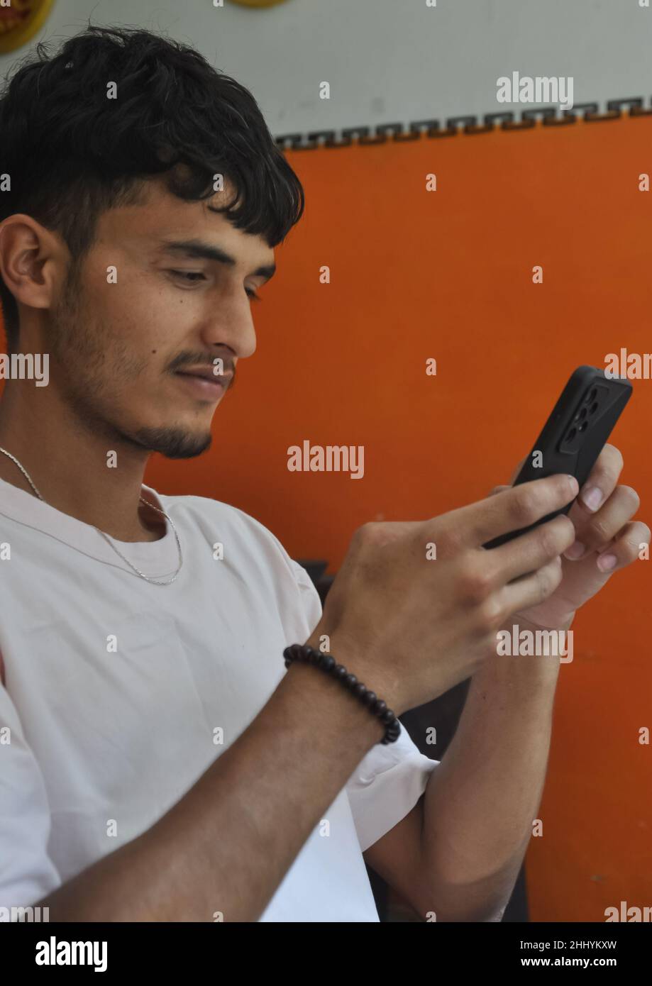Side view of a good looking young men using phone while sitting indoors ...