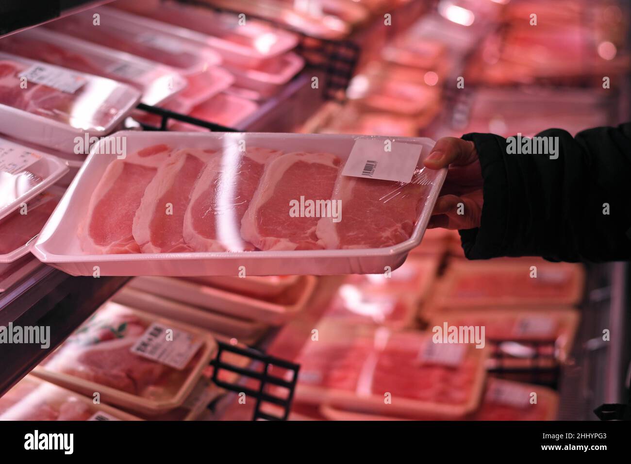 A hand getting a pack of pork at the meat corner of a supermarket Stock ...