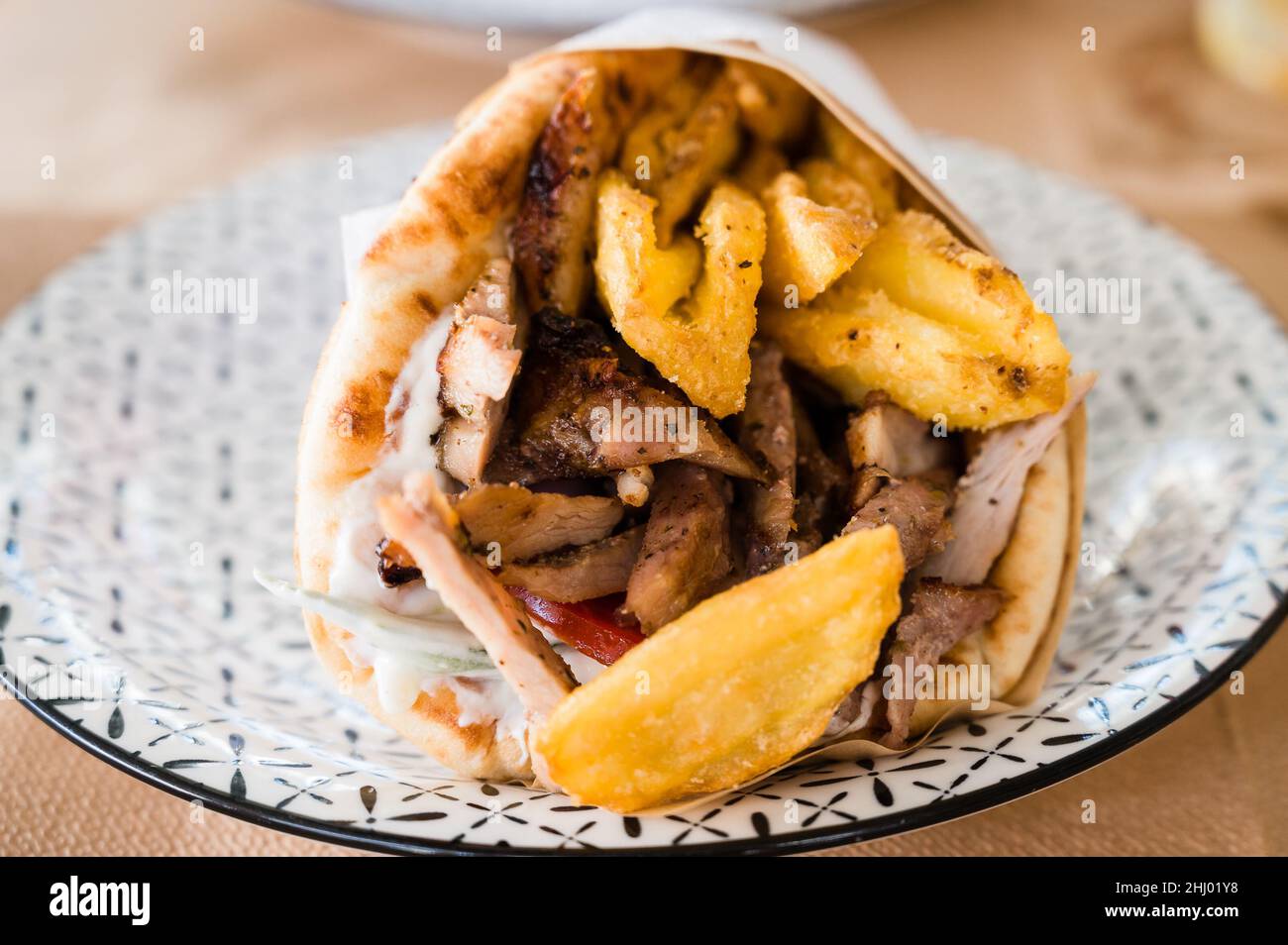 Traditional Greek food gyros pita with fries, vegetables and tzatziki ...