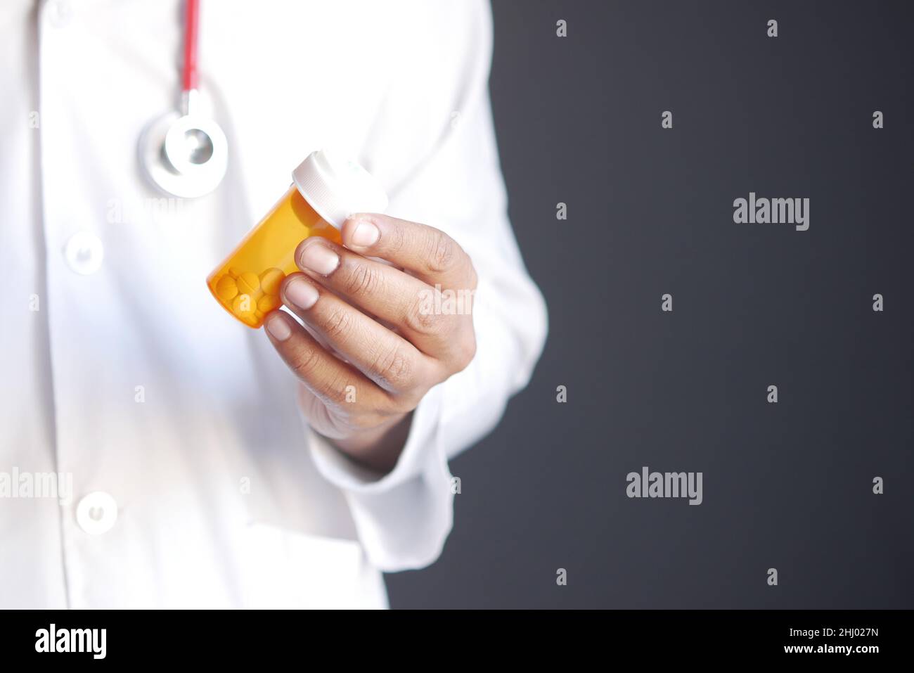 doctor holding pill container on black background Stock Photo - Alamy