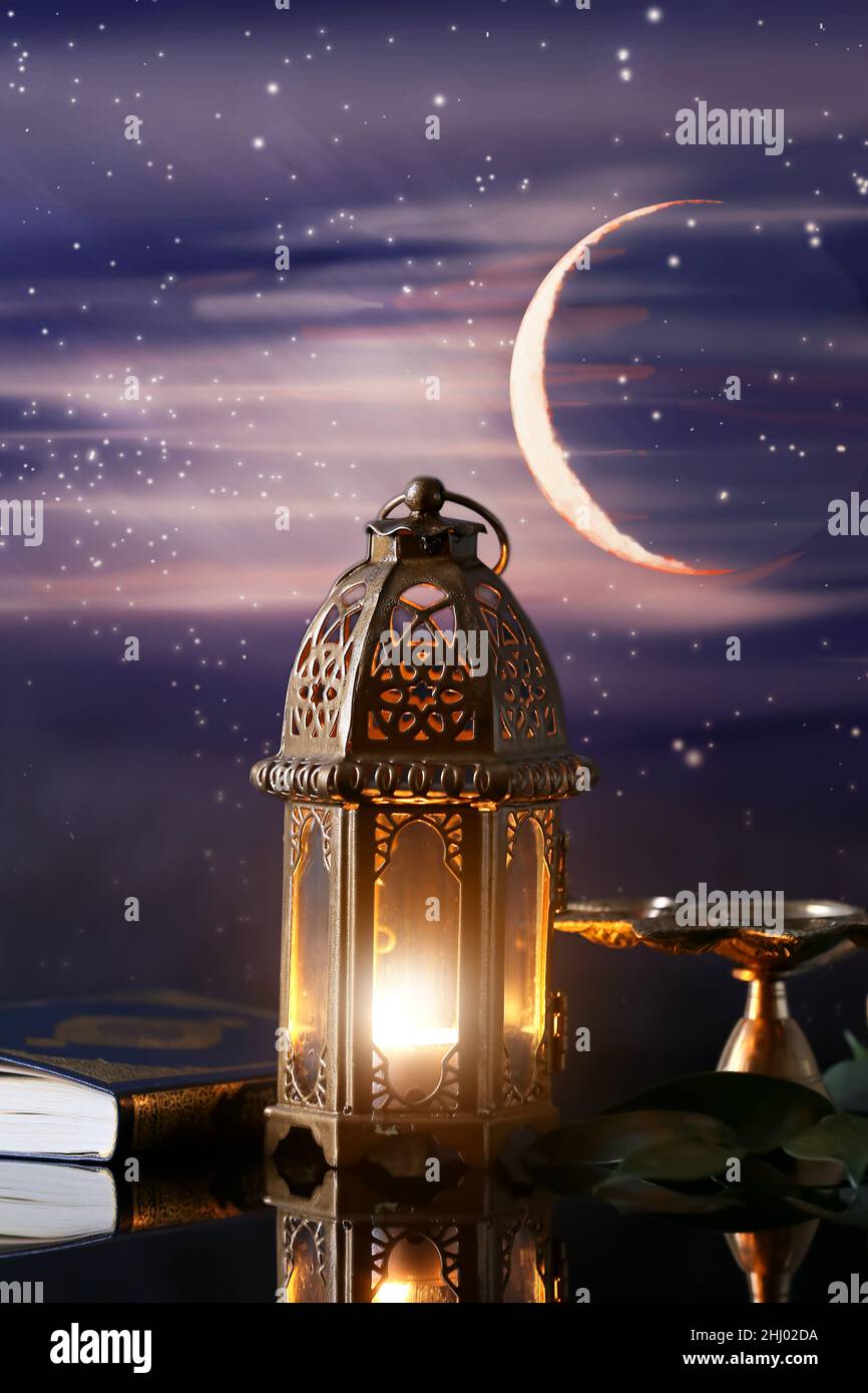 Glowing Muslim lamp and Quran on table at night. Ramadan celebration ...