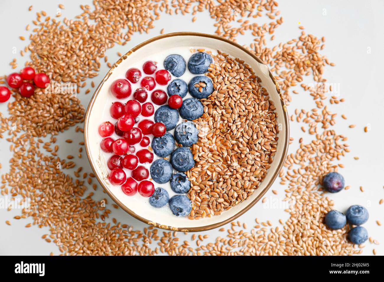Bowl of sweet yogurt with flax seeds and berries on light background ...
