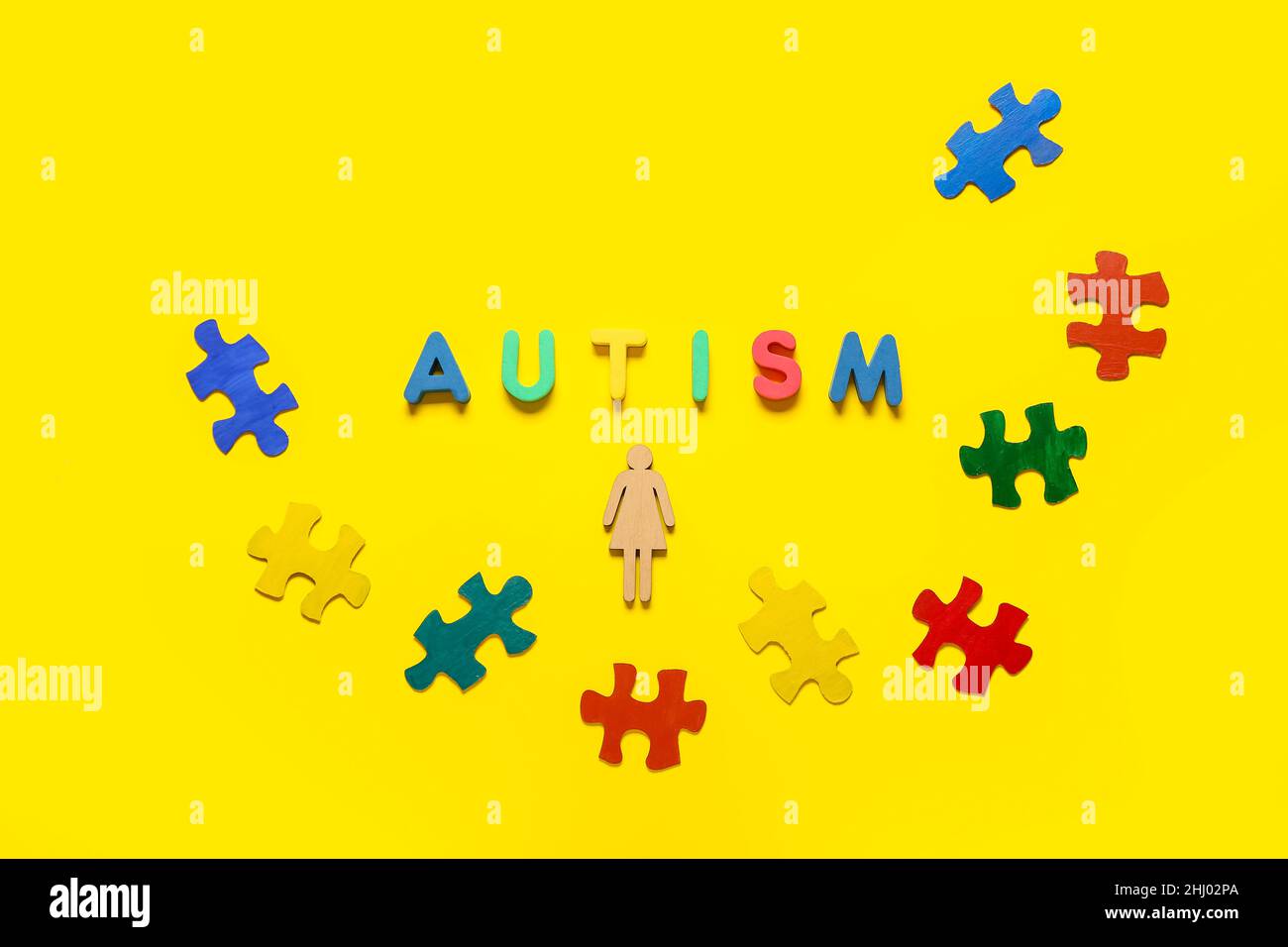 Word AUTISM with colorful puzzle pieces and human figure on color ...