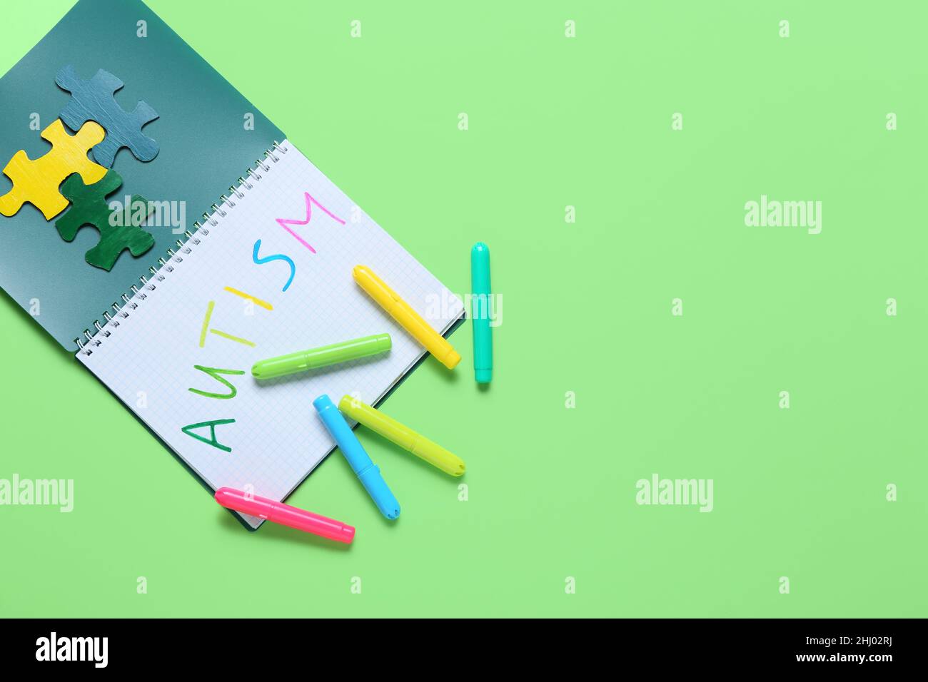 Notebook with word AUTISM, colorful markers and puzzle pieces on color ...