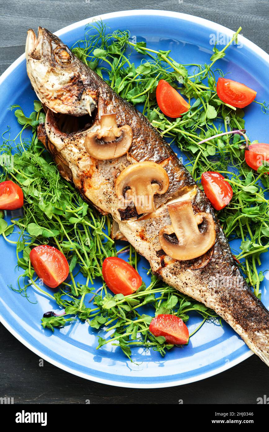 Plate with delicious sea bass fish, microgreens and tomatoes, closeup ...