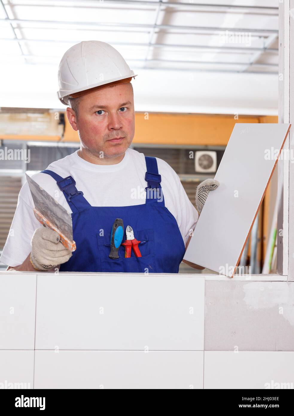 Worker engaged in wall tiling work Stock Photo - Alamy