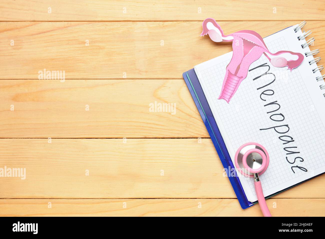 Notebook with word MENOPAUSE, paper uterus and stethoscope on light ...