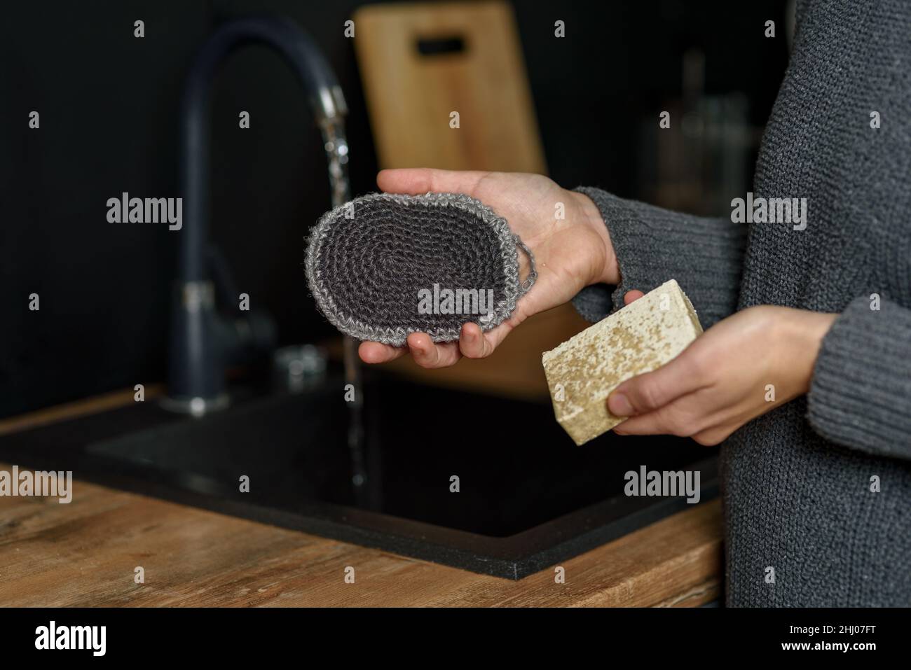 Hand holding natural reusable handmade knitted jute wash cloth with eco ...