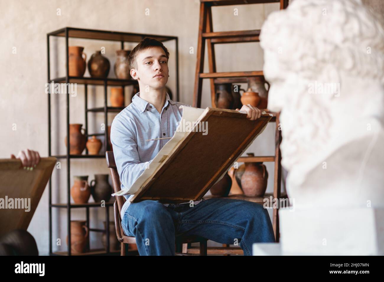 Young white student drawing plaster bust during class in art school ...