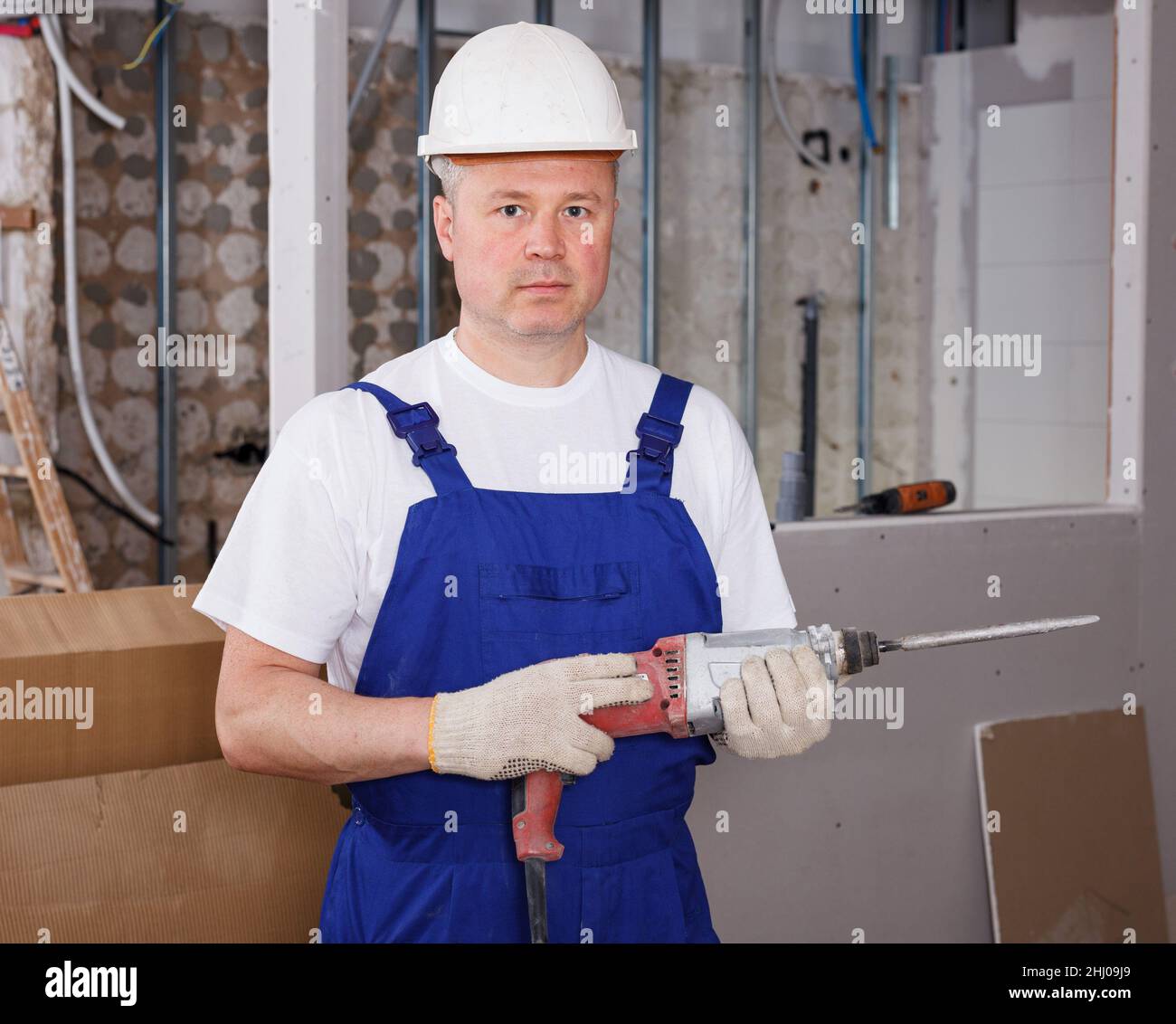 Builder working with drill Stock Photo - Alamy