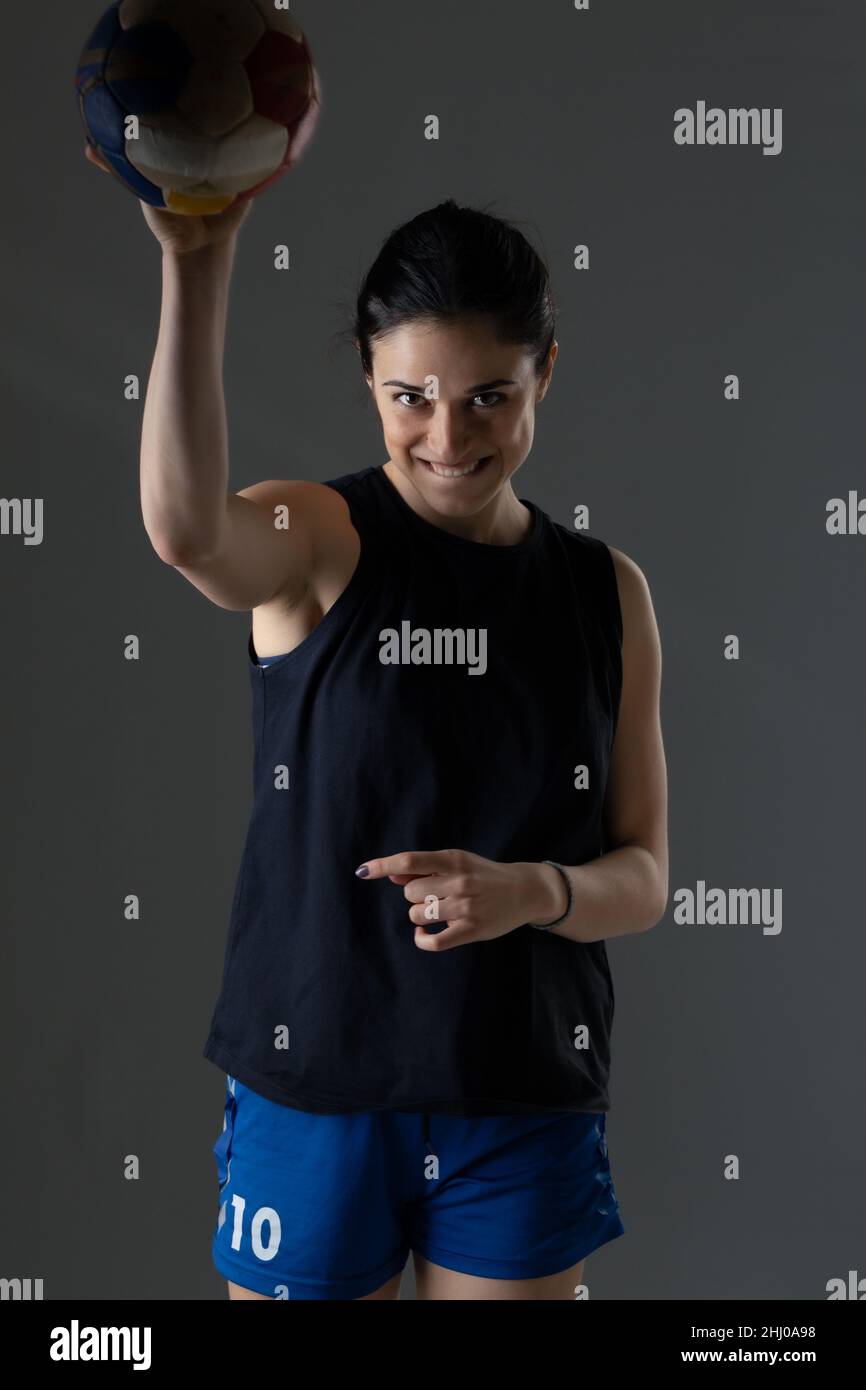 Handball player posing on dark gray background. Girl posing with ball ...