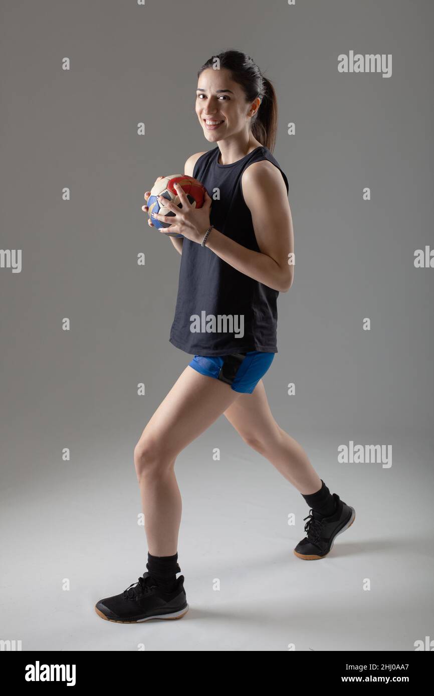 Handball player posing on light gray background. Girl posing with ball ...