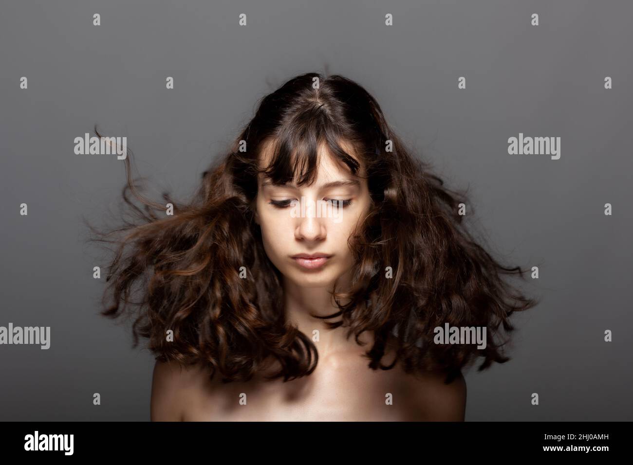 Beautiful young girl studio portrait on gray background. Looking at camera. Windy hair Stock ...