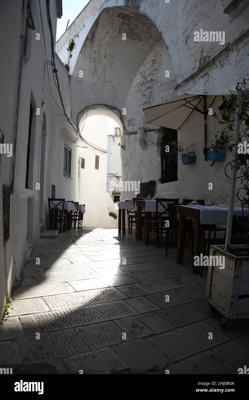 Tables and chairs outside a restaurant inside the old city of Ostuni ...