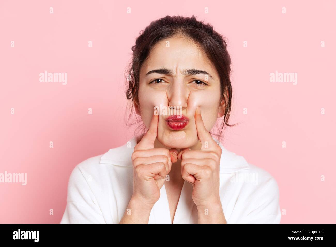 Portrait of young beautiful funny girl in white blouse making fish face ...