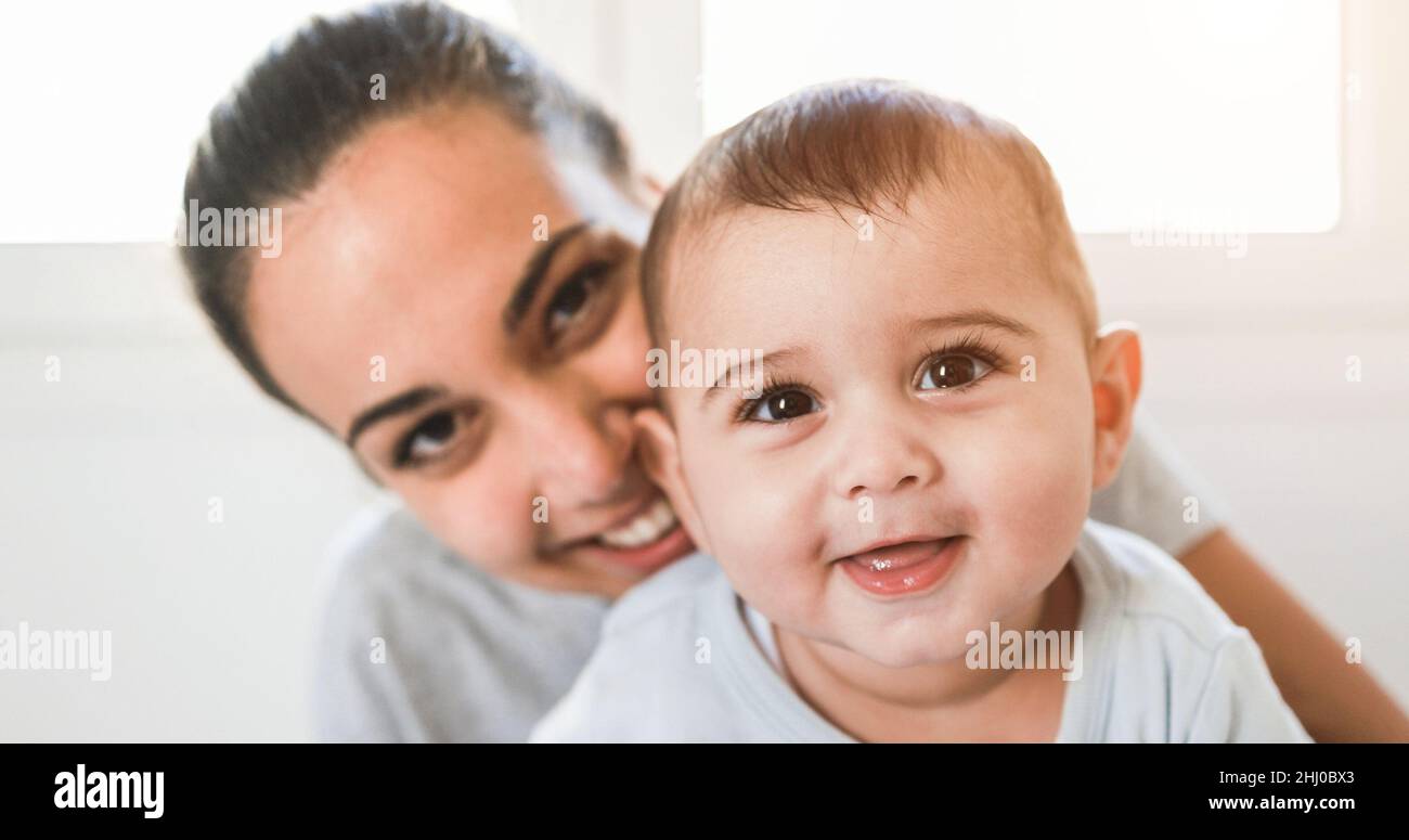 Portrait of young mother and baby looking at camera indoor at home ...