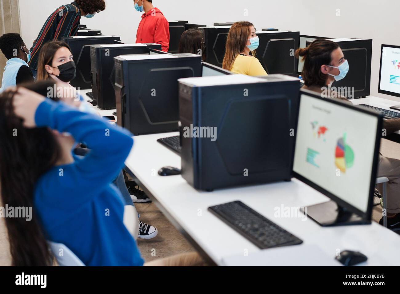Multiracial young students using computers during coronavirus outbreak ...