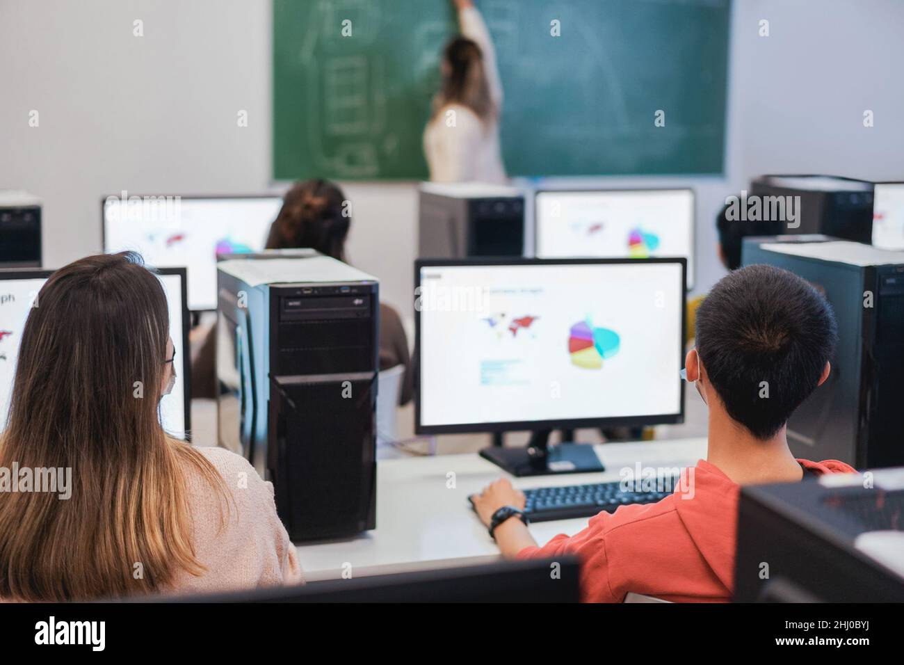 Multiracial students using computers during business class wearing ...