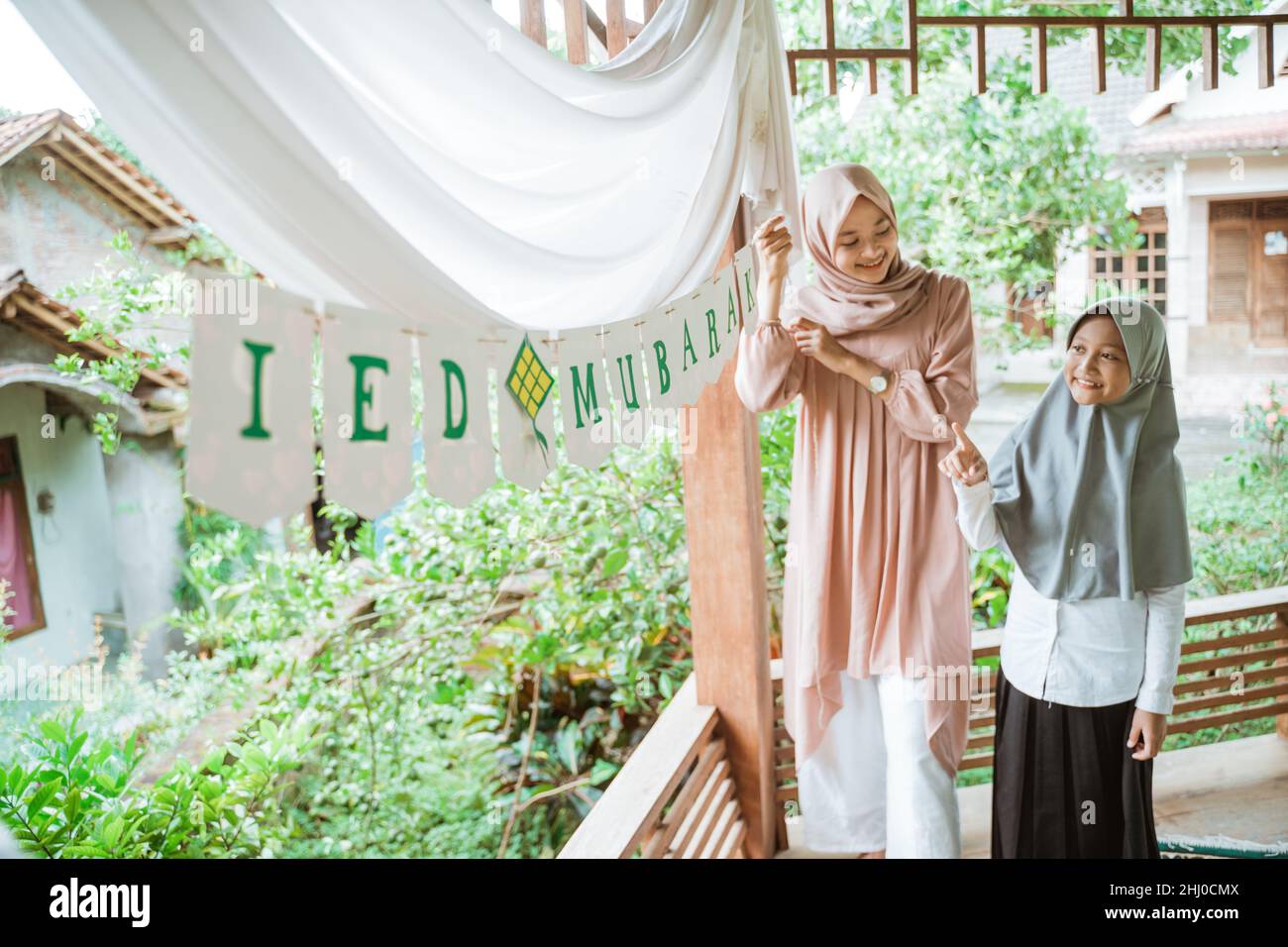 mother putting up a paper flag chain decoration with daughter Stock ...