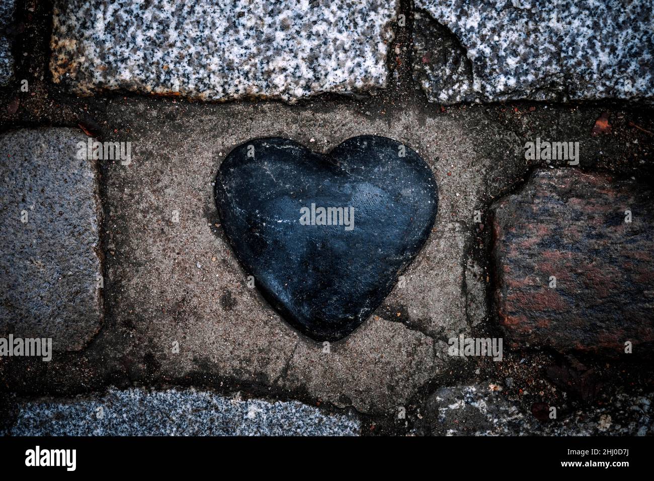Black heart shaped rock on a tile background. concept of love and life ...